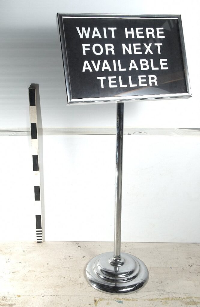 Sign – “Wait here for the next available teller” – PropCo